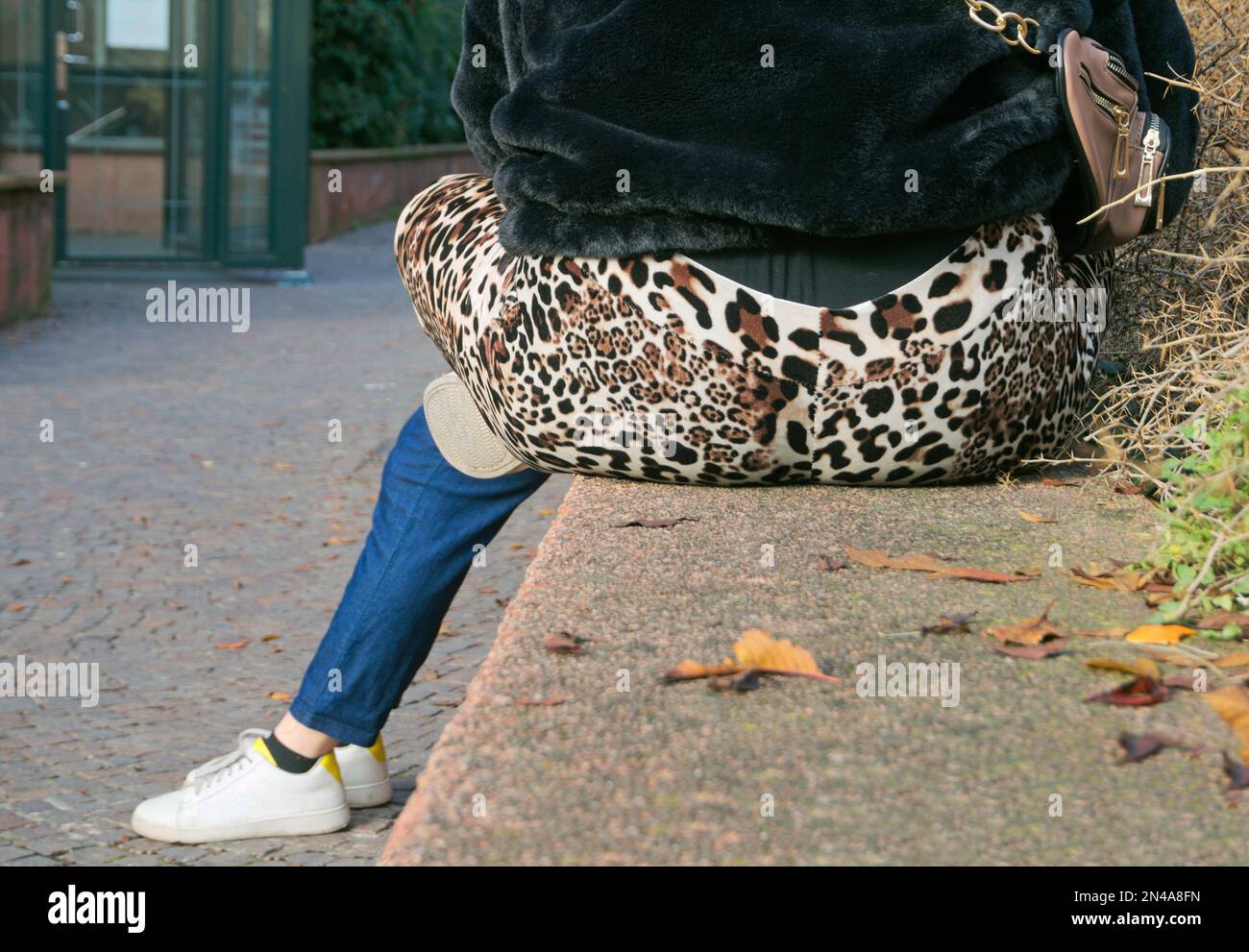 rear view of a woman with leopard print spotted pants sitting outside ...