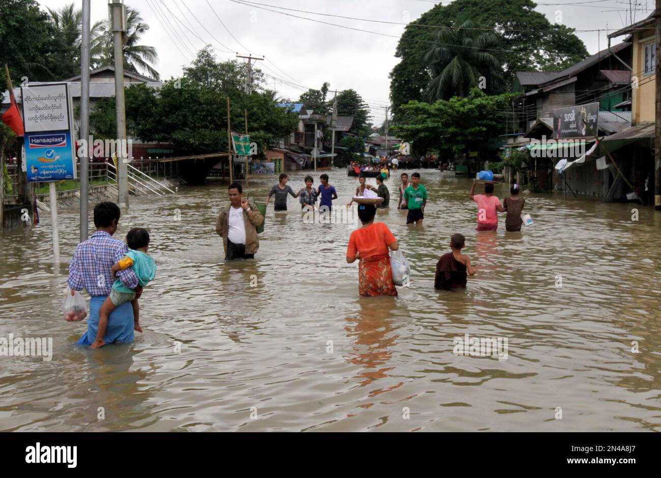 People wade through a flooded street after the Bago River was swollen ...