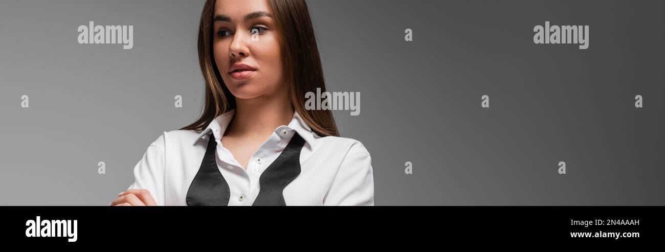 portrait of confident woman in white shirt and black tie looking away ...