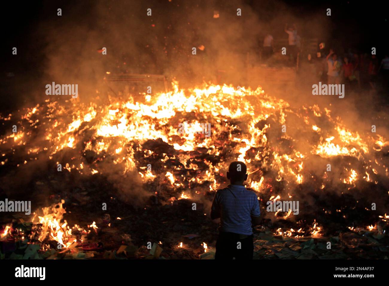 An ethnic Chinese man offers a prayer after a paper-made statue of ...