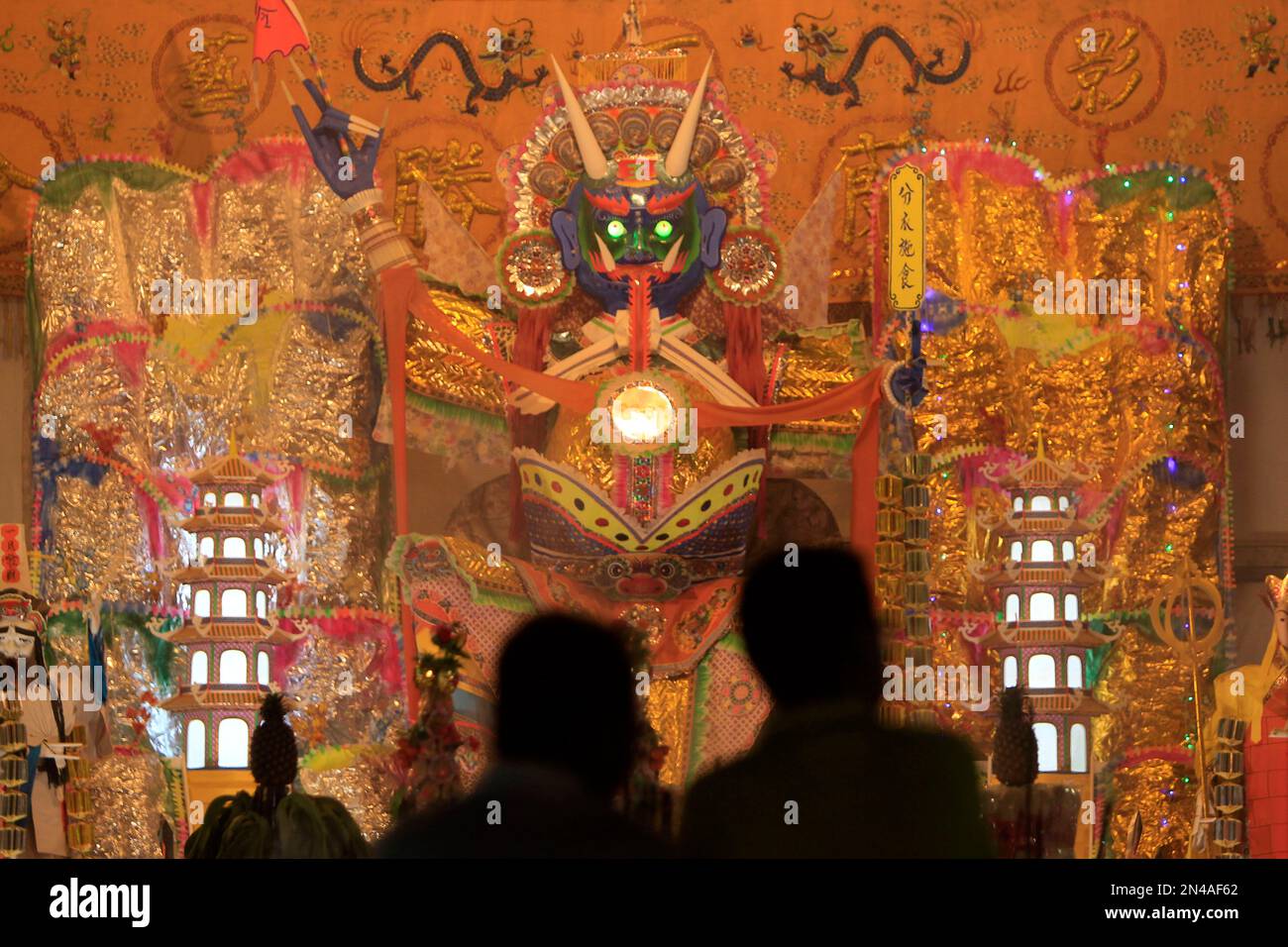 Ethnic Chinese offer a prayer in front of a paper-made statue of ...