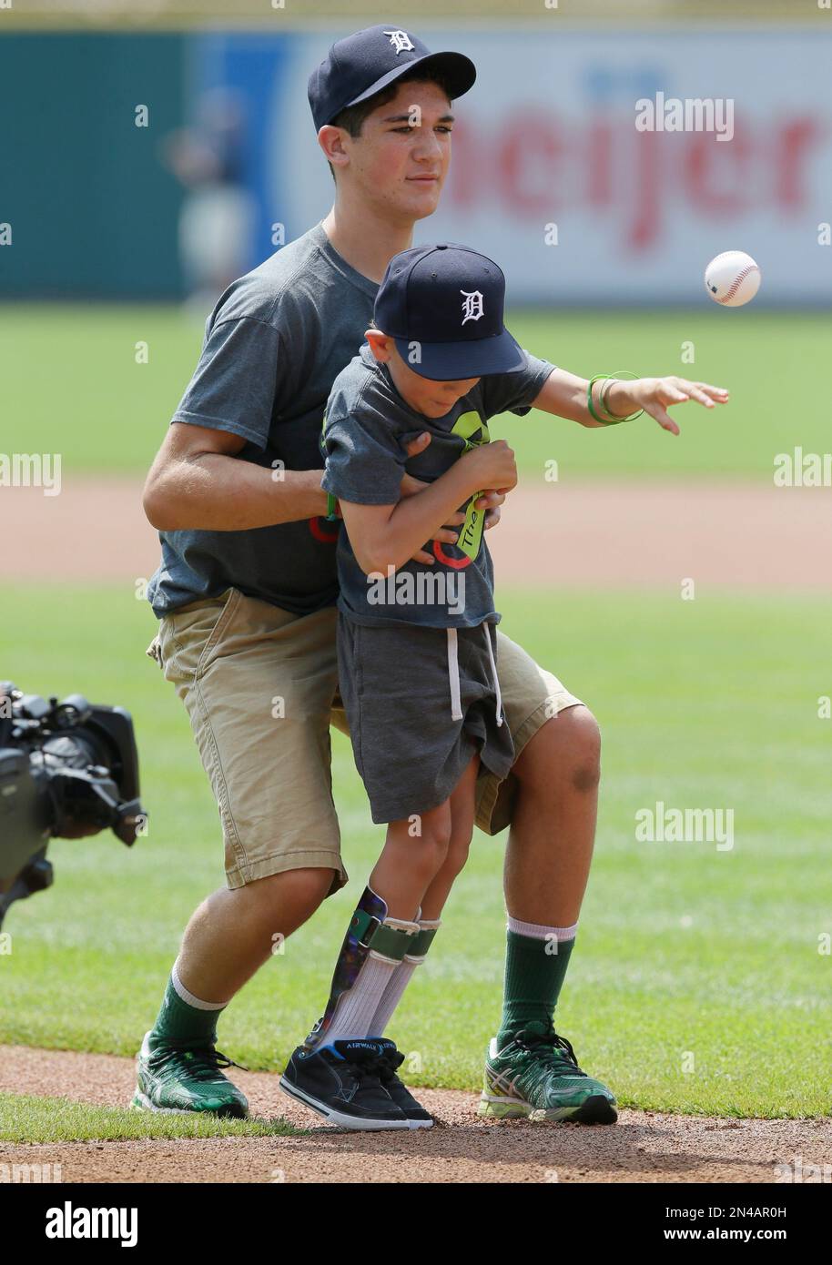 Braden Gandee, 7, held by his brother Hunter tosses the ceremonial ...