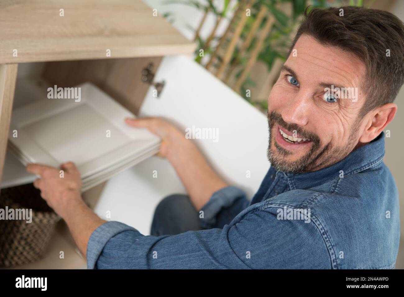 man sorting the dishes in a kitchen cupboard Stock Photo - Alamy