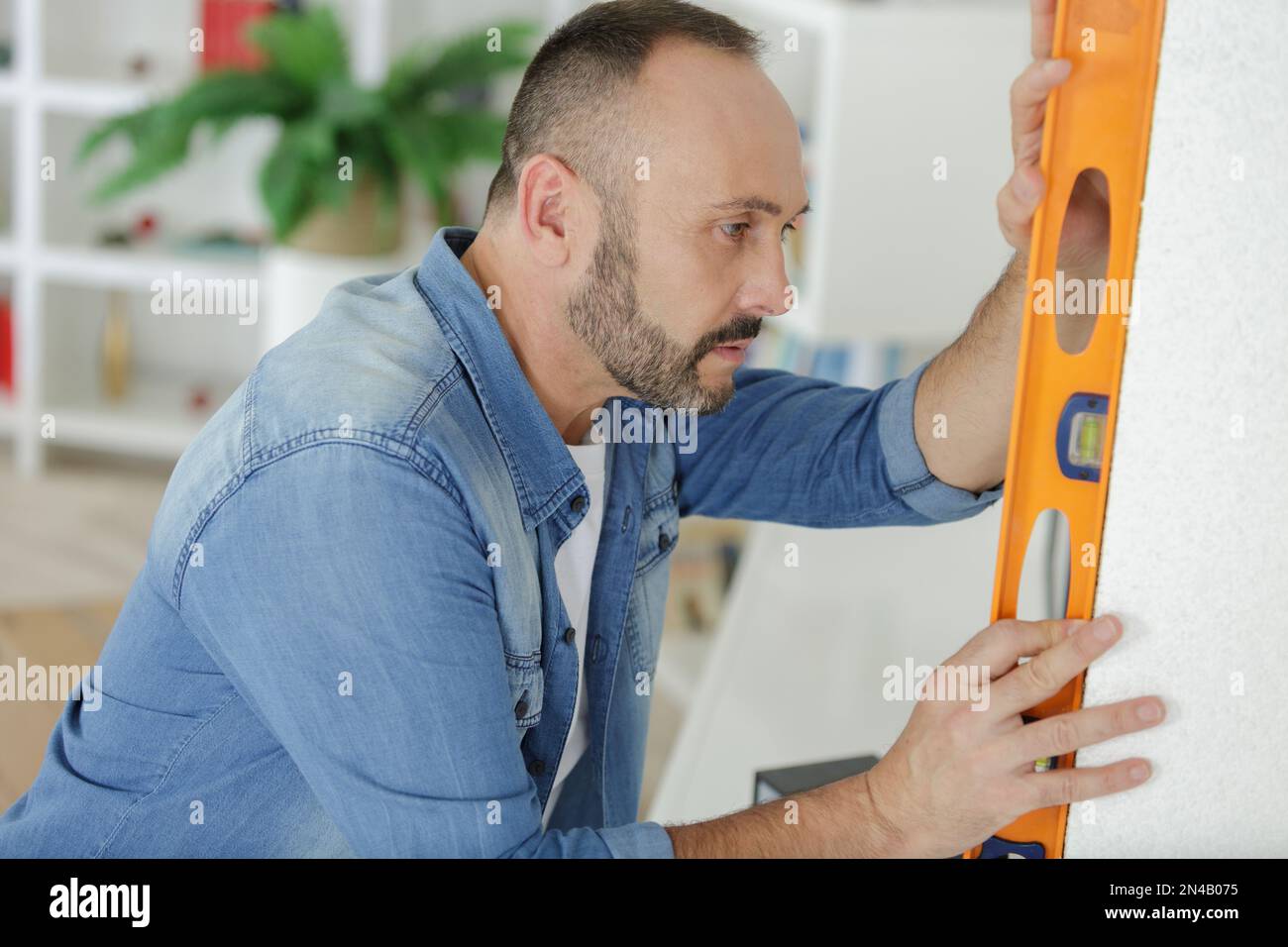 man measuring wall with level Stock Photo - Alamy