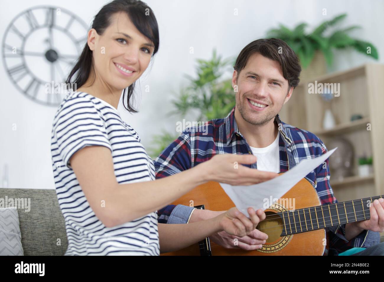 boyfriend playing guitar song from sheet music Stock Photo - Alamy