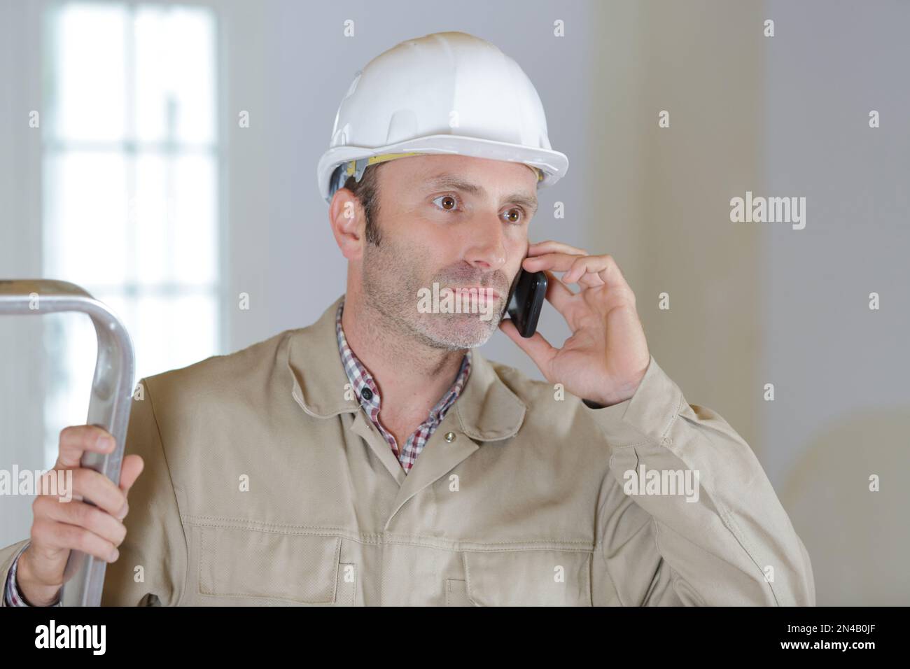 builder on the phone by a ladder Stock Photo - Alamy