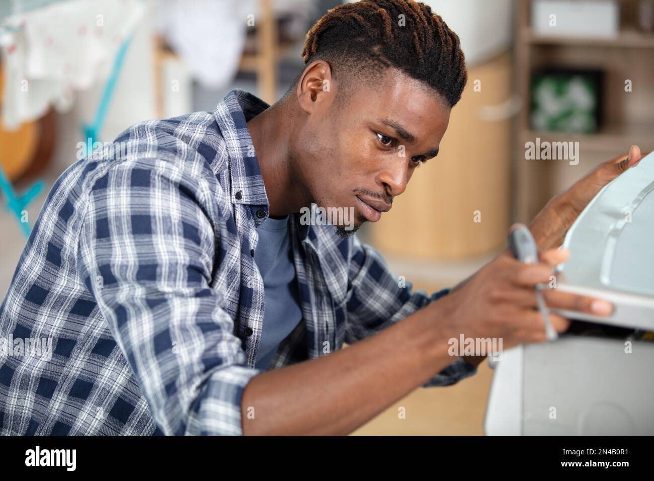 washing machine repairman concentrating on reassembling machine Stock ...