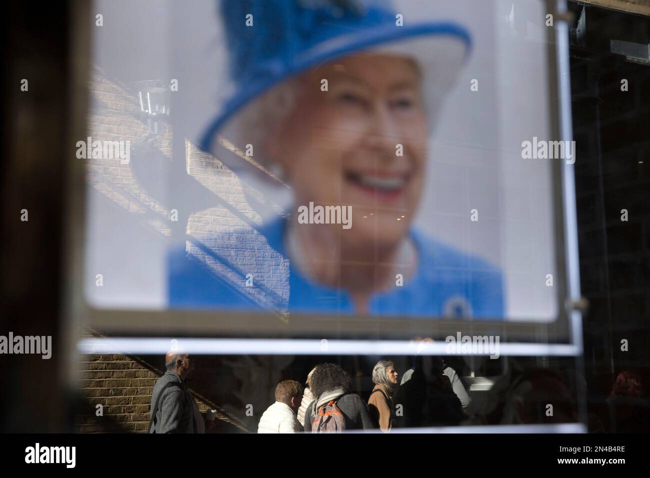 People are reflected in a shop window where a portrait of the late ...