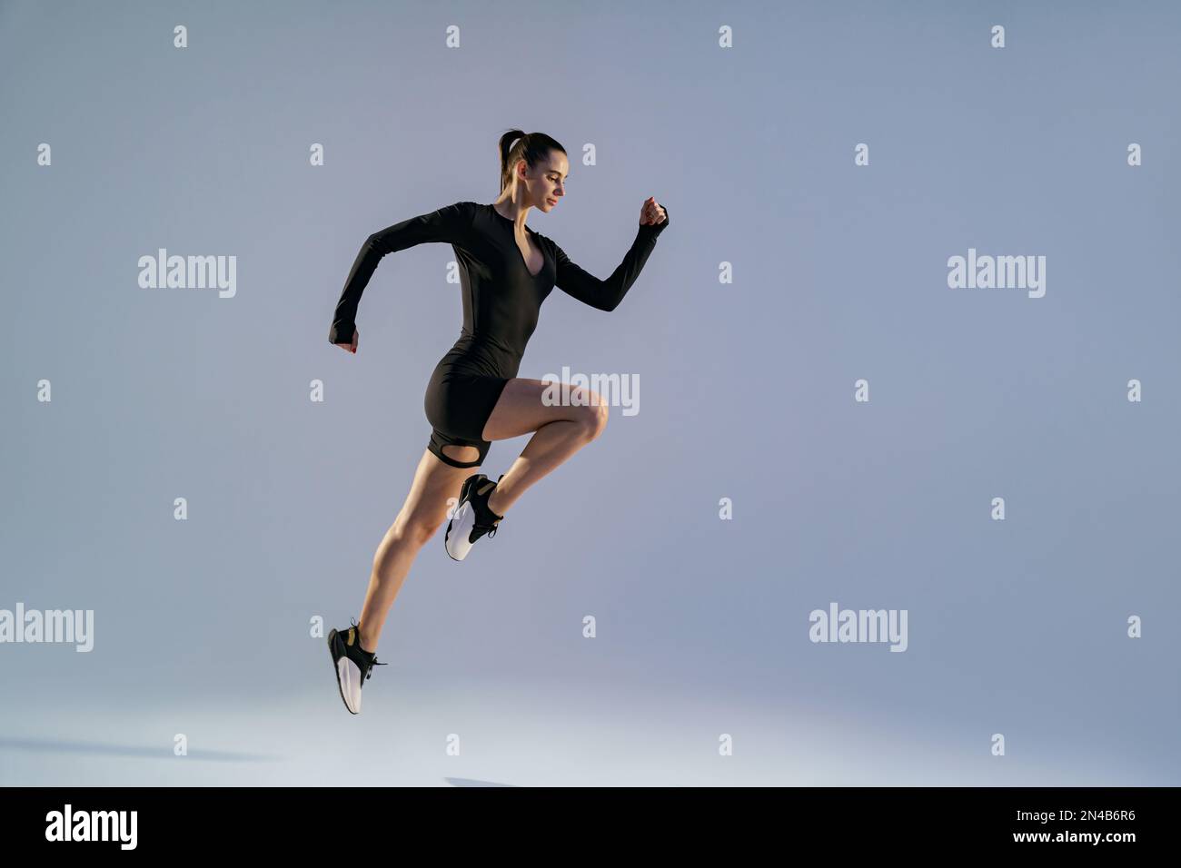 Smiling sporty woman running in Mid-Air exercising during cardio ...