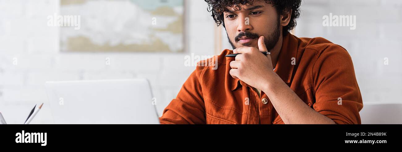 Focused indian freelancer looking at laptop at home, banner,stock image ...