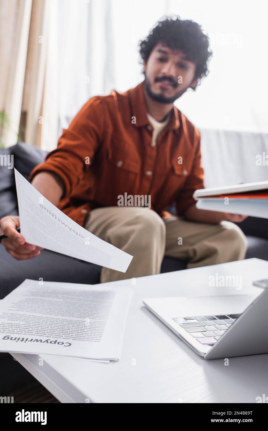 Blurred indian copywriting working on couch in living room,stock image ...