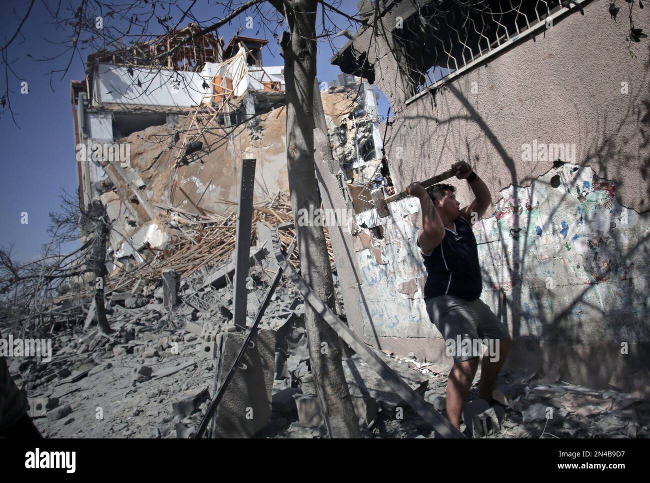 A Palestinian man strikes the walls of his house which caught on fire ...