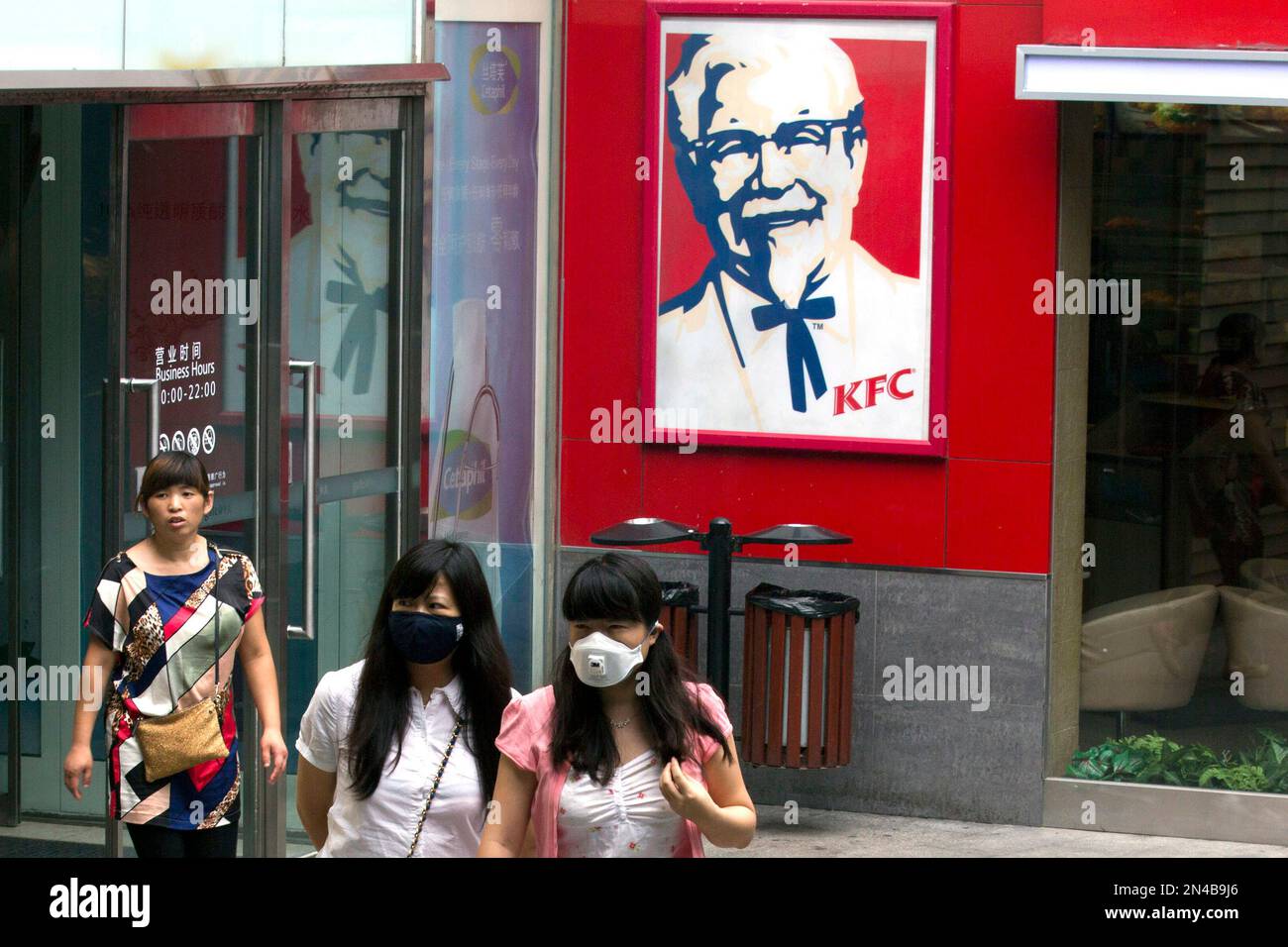Women wearing masks during a polluted day walk outside a KFC restaurant ...