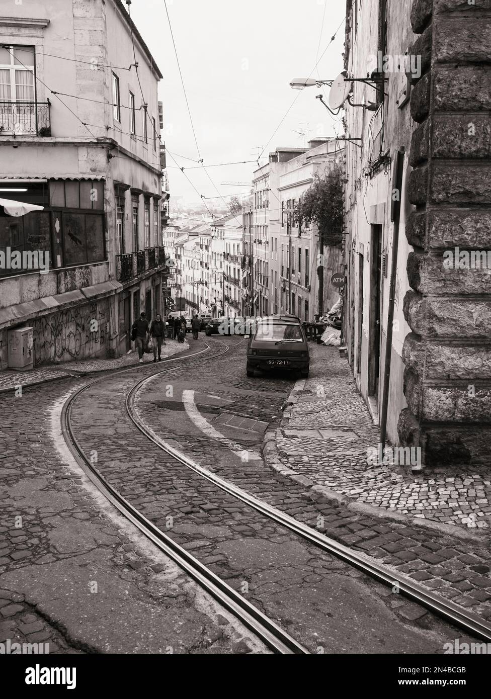 Vertical: Black and white of trolly tracks down the narrow street in ...