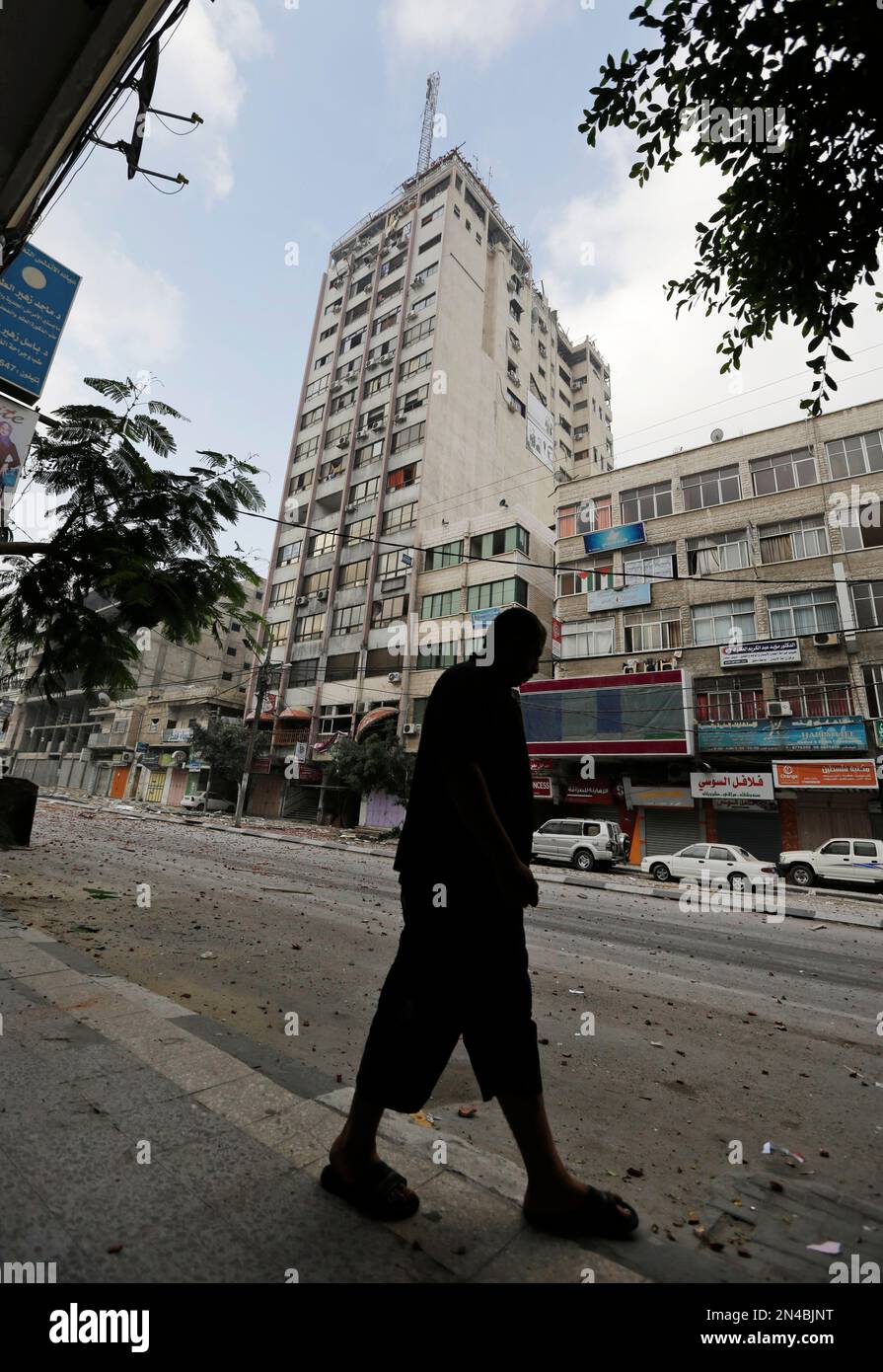A Palestinian walks past the Al Shorouk tower, hit by an overnight ...