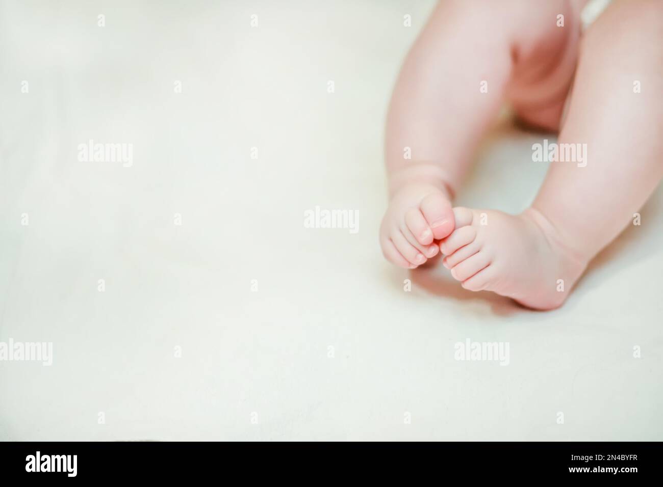 The legs of the baby 2-5 months folded her fingers together. tiny legs ...