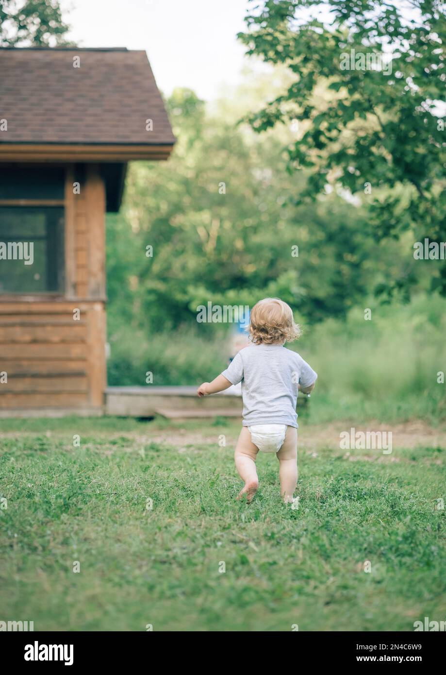 A vertical shot of a toddler in diapers running in the backyard Stock ...