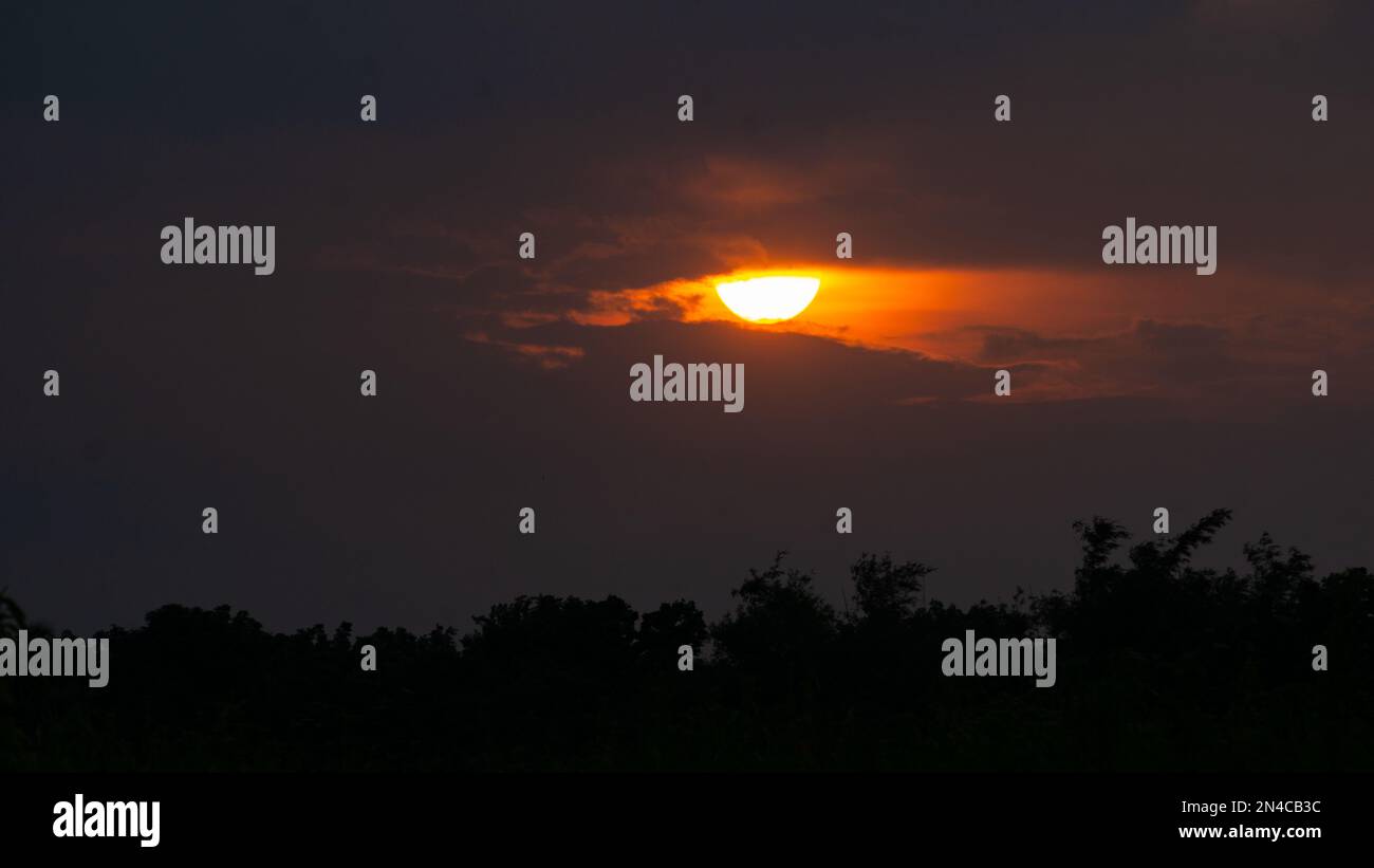 The golden sun is sinking in the sky of the village of Bangladesh. This ...