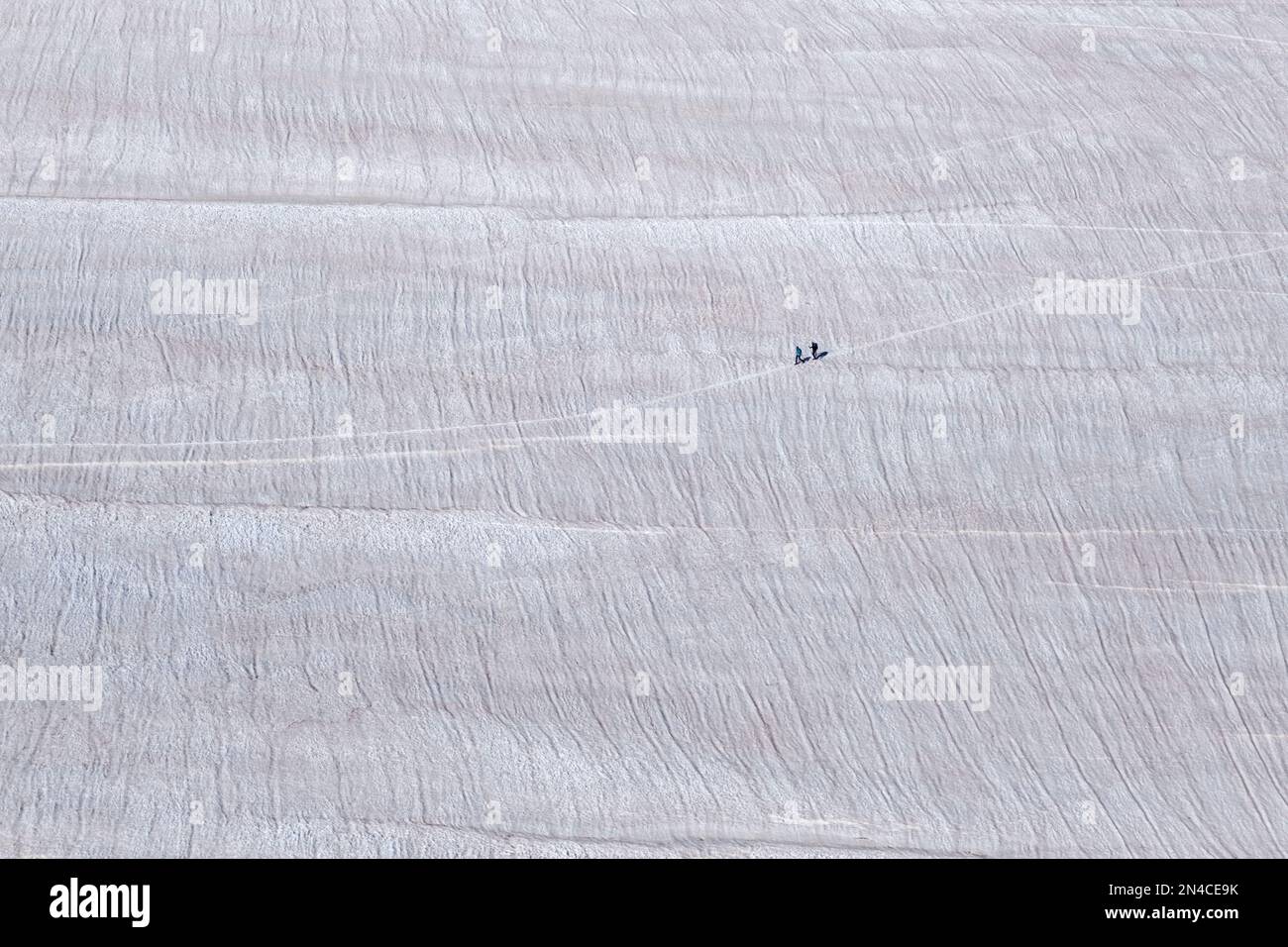 Aerial view of two alpinists crossing the slopes of the upper part of ...