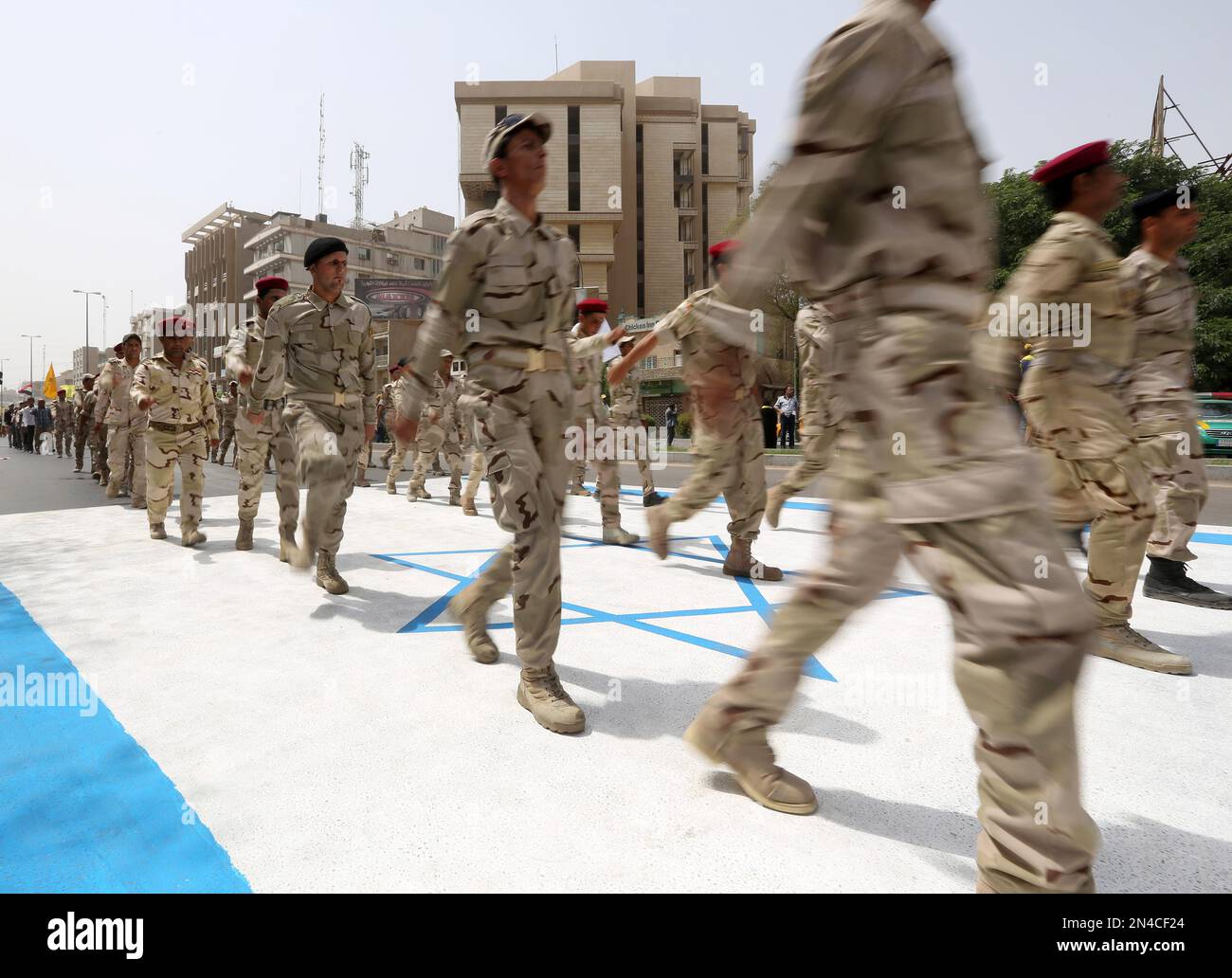 Supporters of Iraqi Hezbollah brigades marching in military uniforms ...