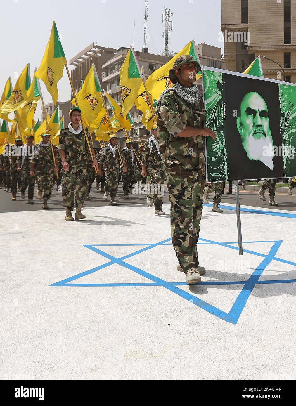 Supporters of Iraqi Hezbollah brigades marching in military uniforms ...