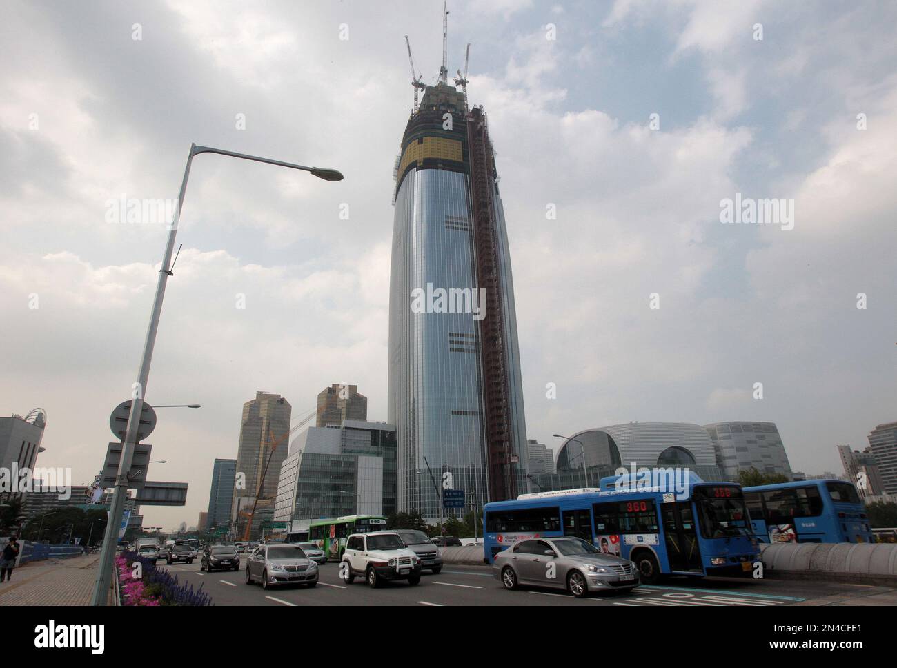 In this July 8, 2014, vehicles pass by the Lotte World Tower, center ...