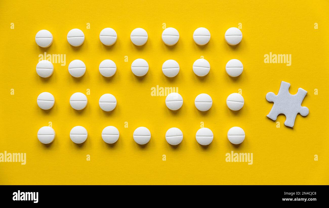 A row of white medical pills on yellow background with one missing spot ...