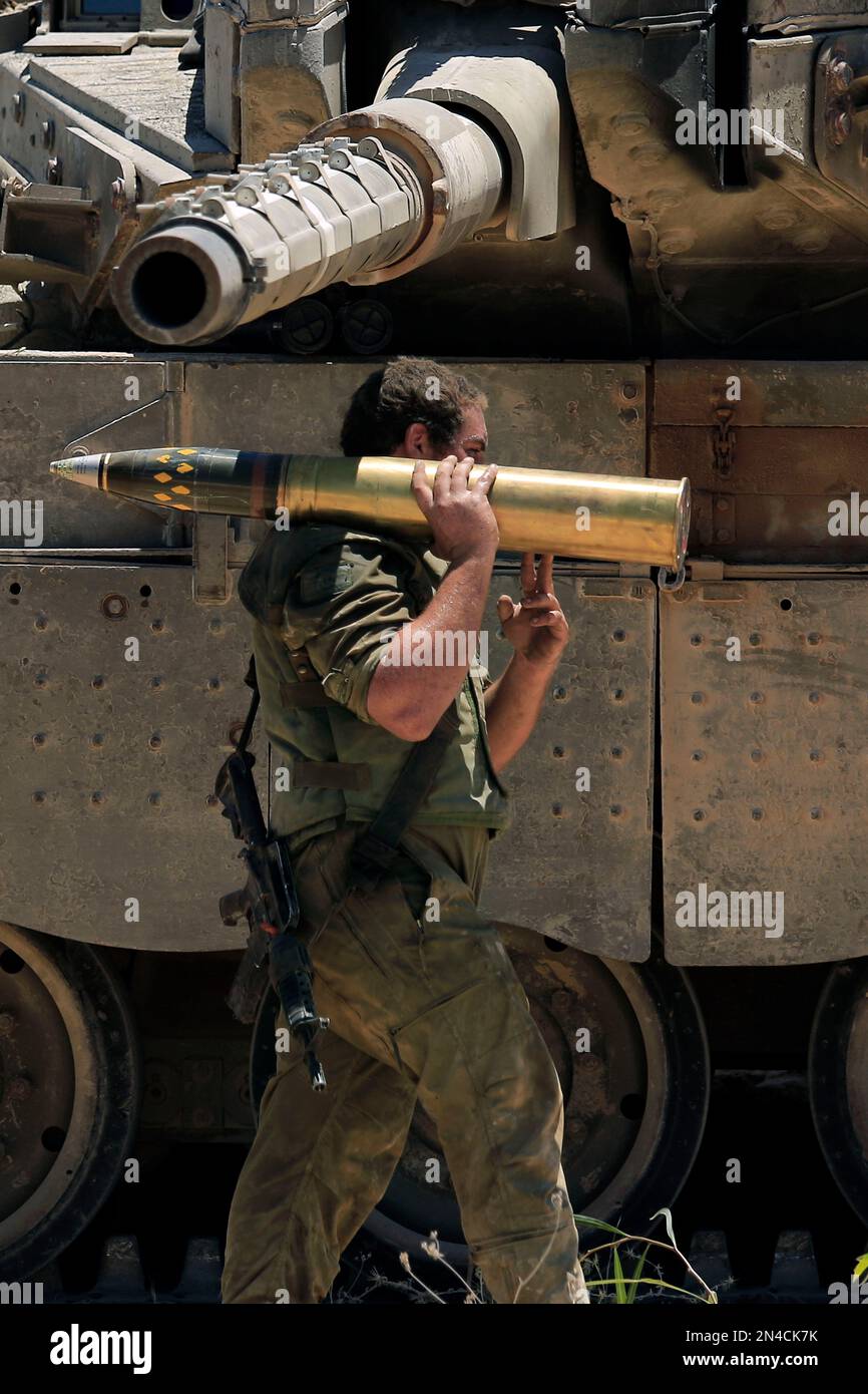 An Israeli soldier carries a tank shell near the Israel and Gaza border ...
