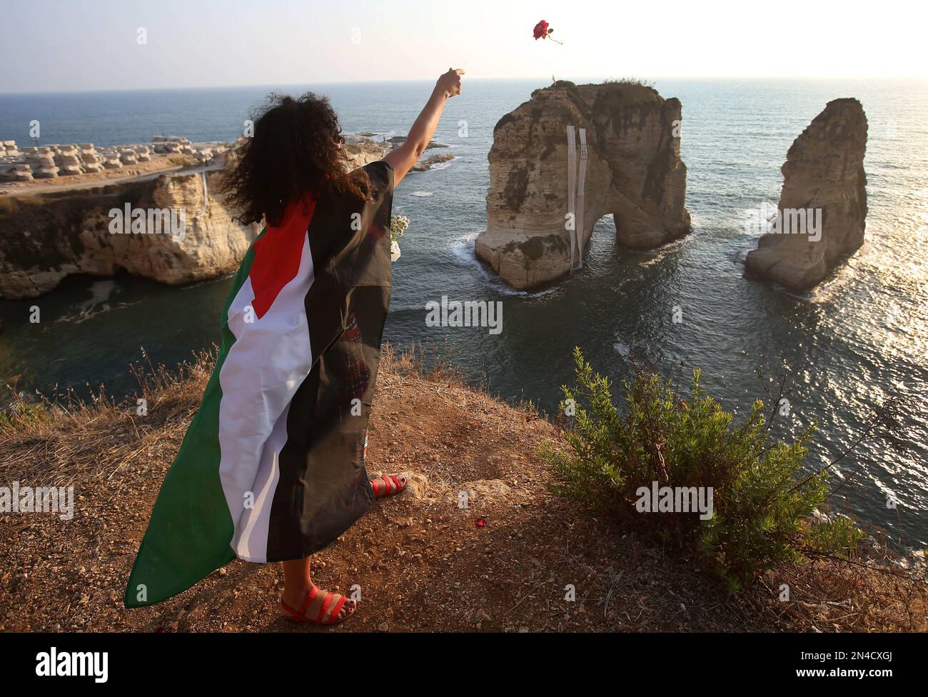 A Lebanese activist wearing a Palestinian flag throws flower in the sea ...