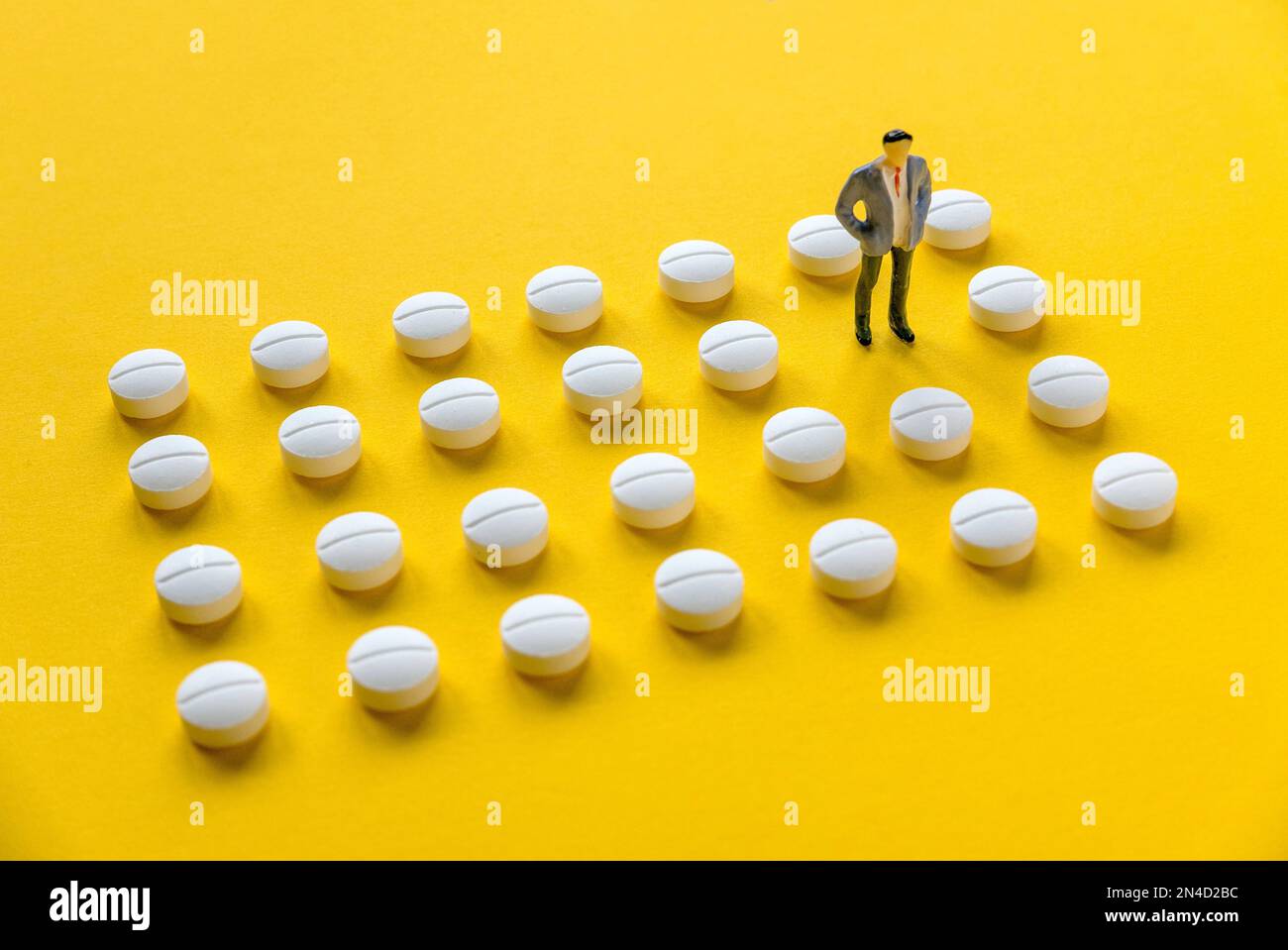 A row of white medical pills on yellow background with one missing spot ...