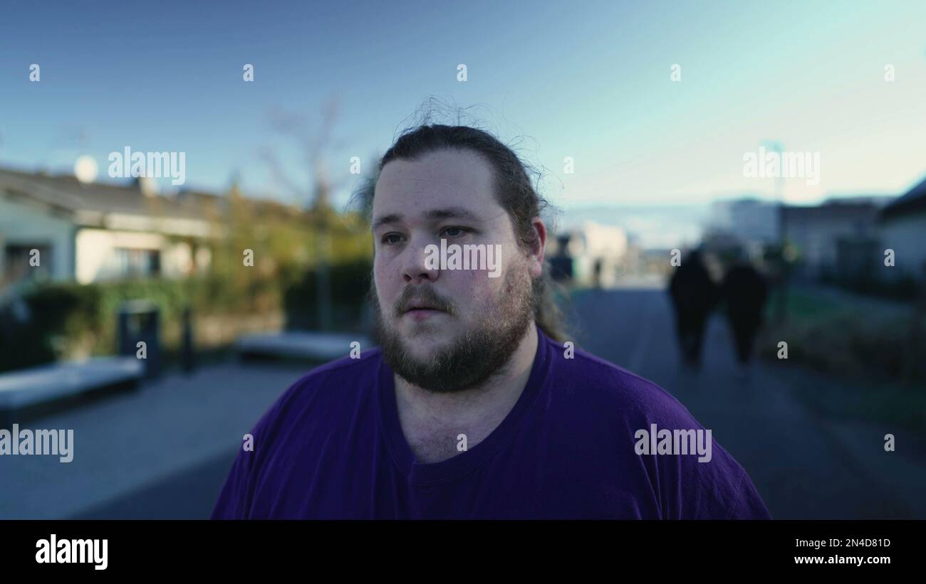 One pensive overweight young man walking outside in street in ...