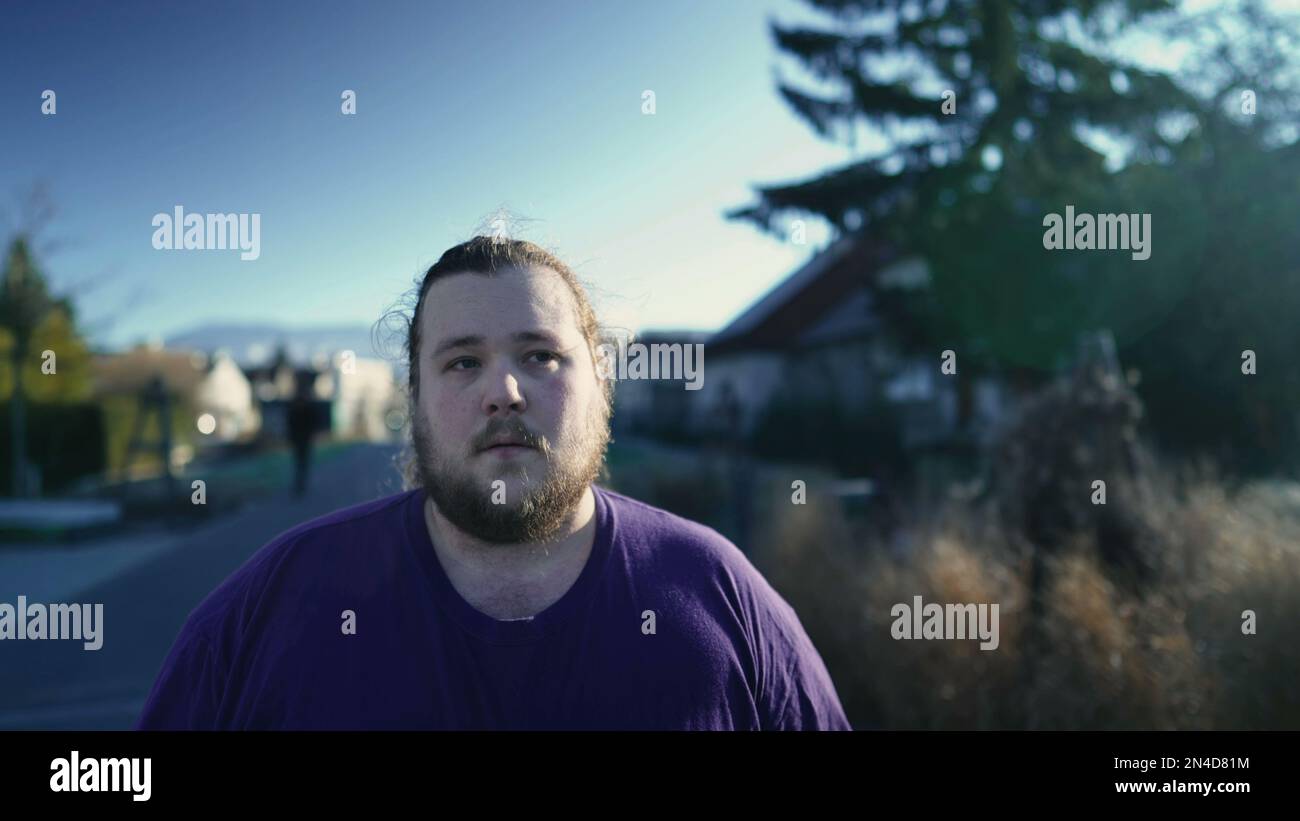 One pensive overweight young man walking outside in street in ...