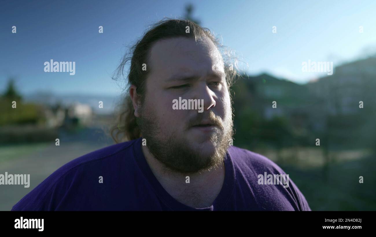 One upset young overweight man walks outside closeup face. Tracking ...
