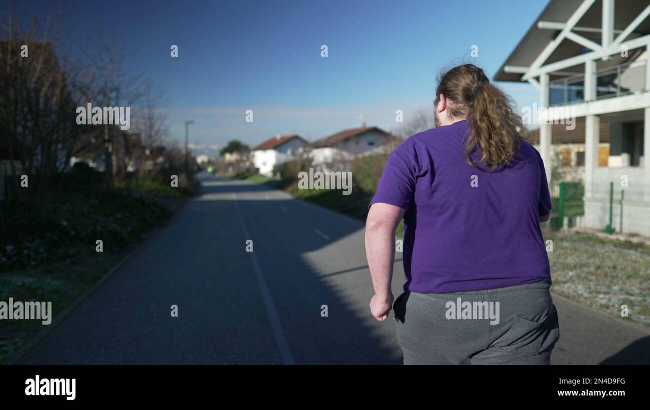 Back of one overweight man running outside in street. A fat person ...