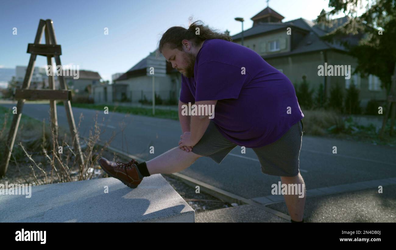 One overweight man stretching legs preparing to exercise outdoors. An ...