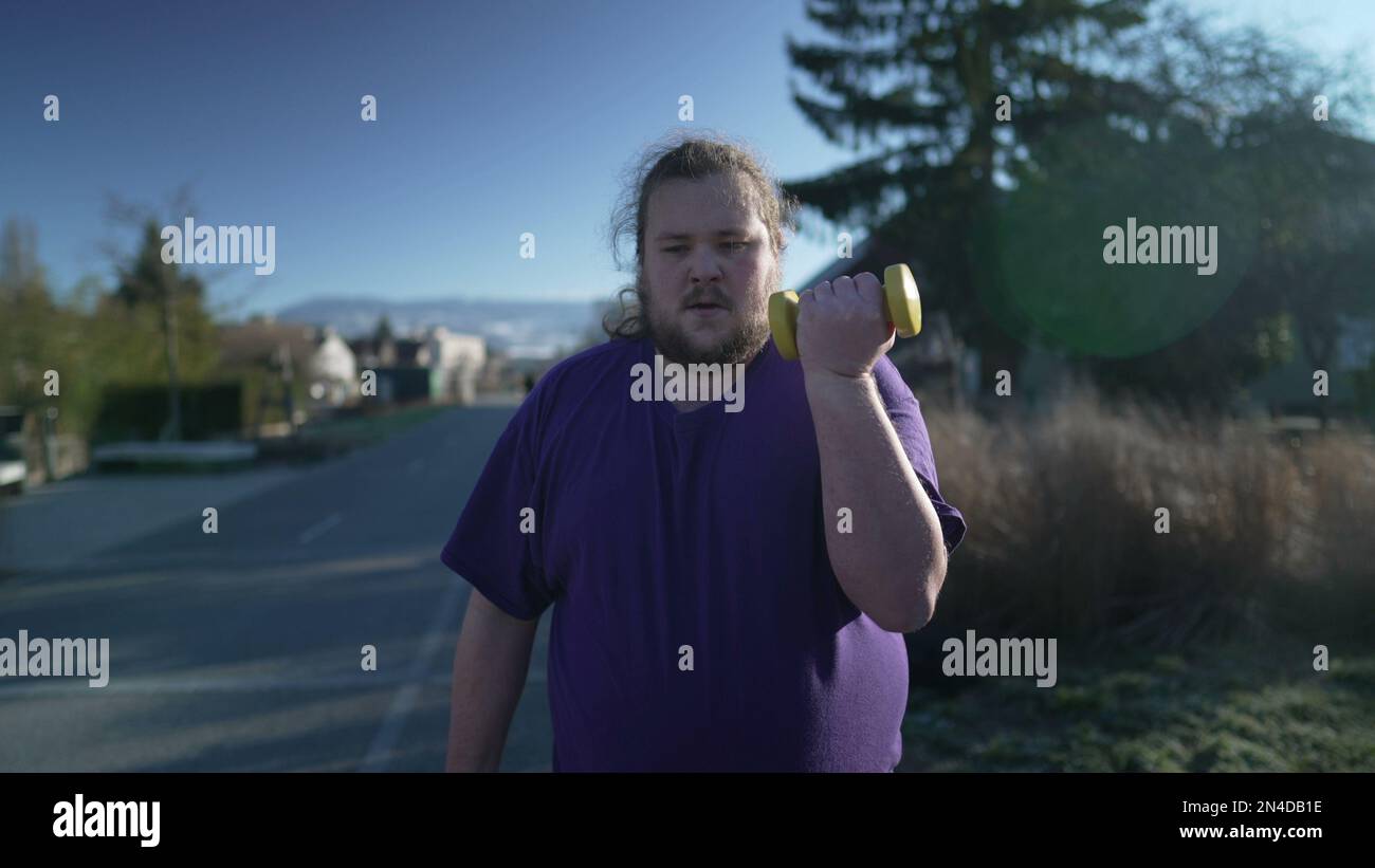 One overweight man lifting weight outside. A determined of fat person ...