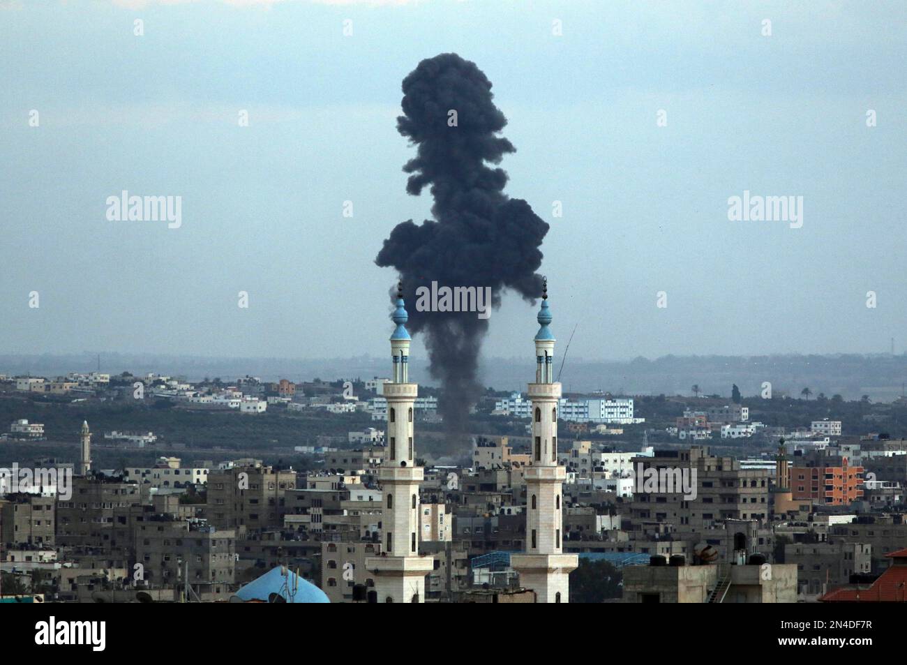 Smoke rises behind a mosque's minarets after an Israeli missile strike ...