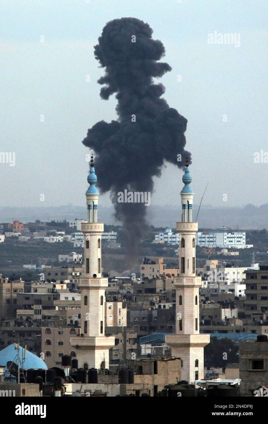 Smoke rises behind a mosque's minarets after an Israeli missile strike ...