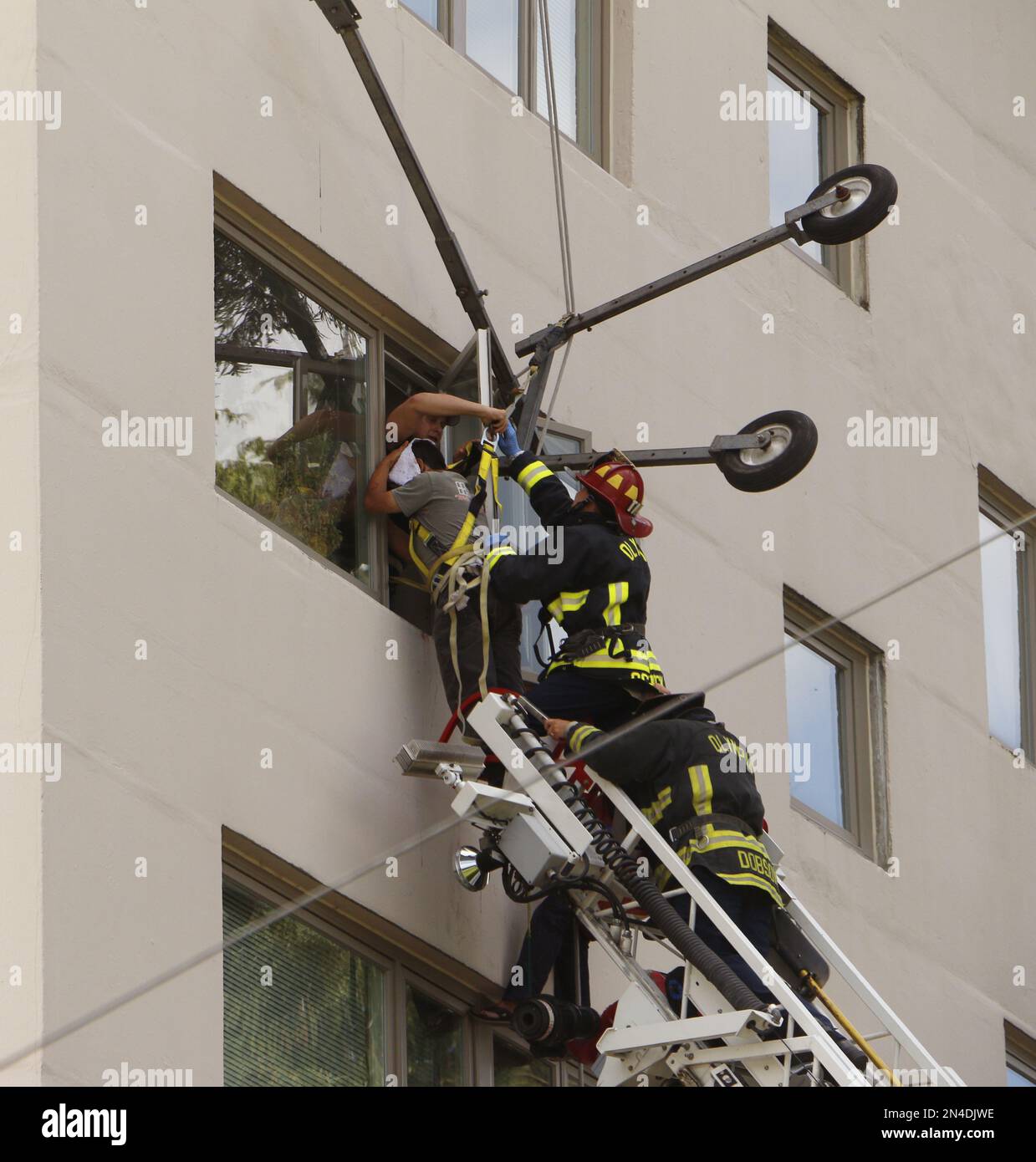 Firefighters use their ladder truck to reach two window washers who ...