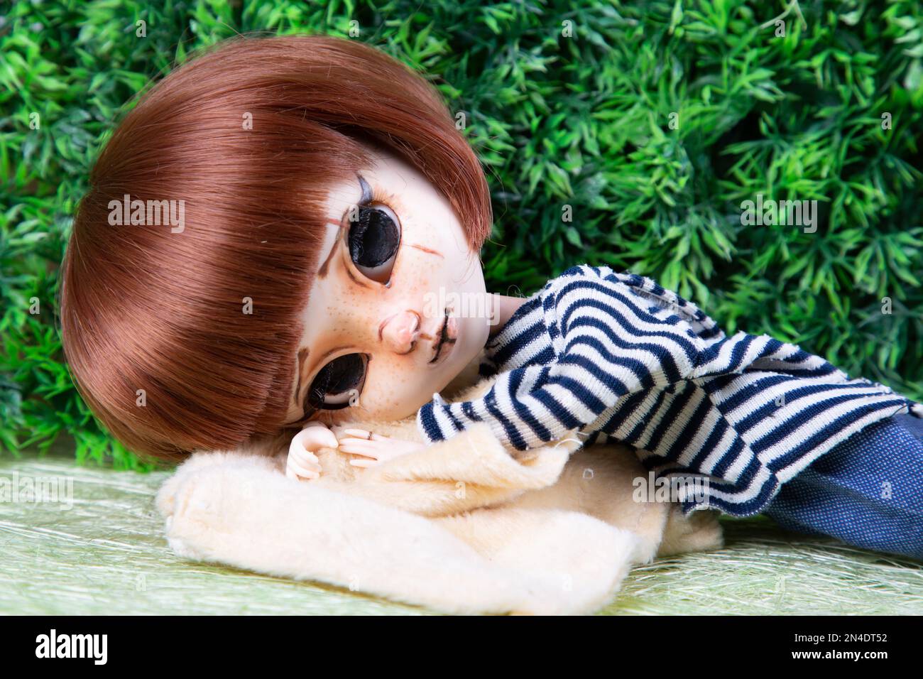 doll red hairs girl lying toy in green plastic background Stock Photo ...