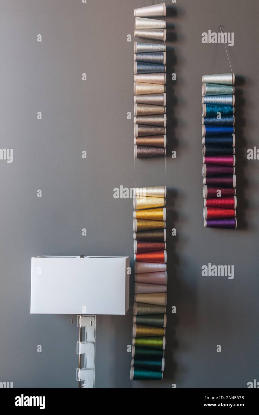 A vertical shot of colorful threads hanging on a gray wall Stock Photo ...