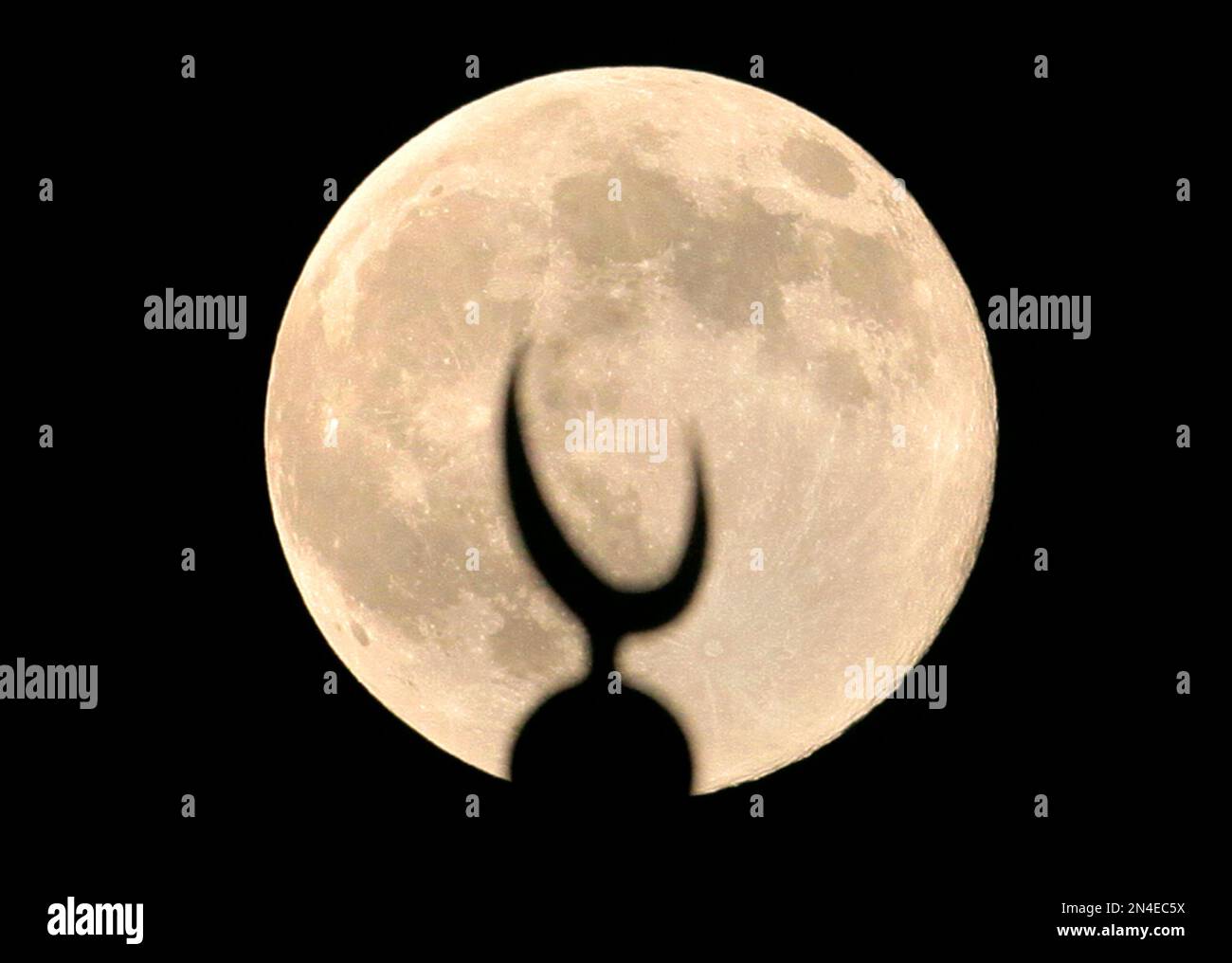 A perigee moon, also known as a supermoon, rises over a crescent of a ...