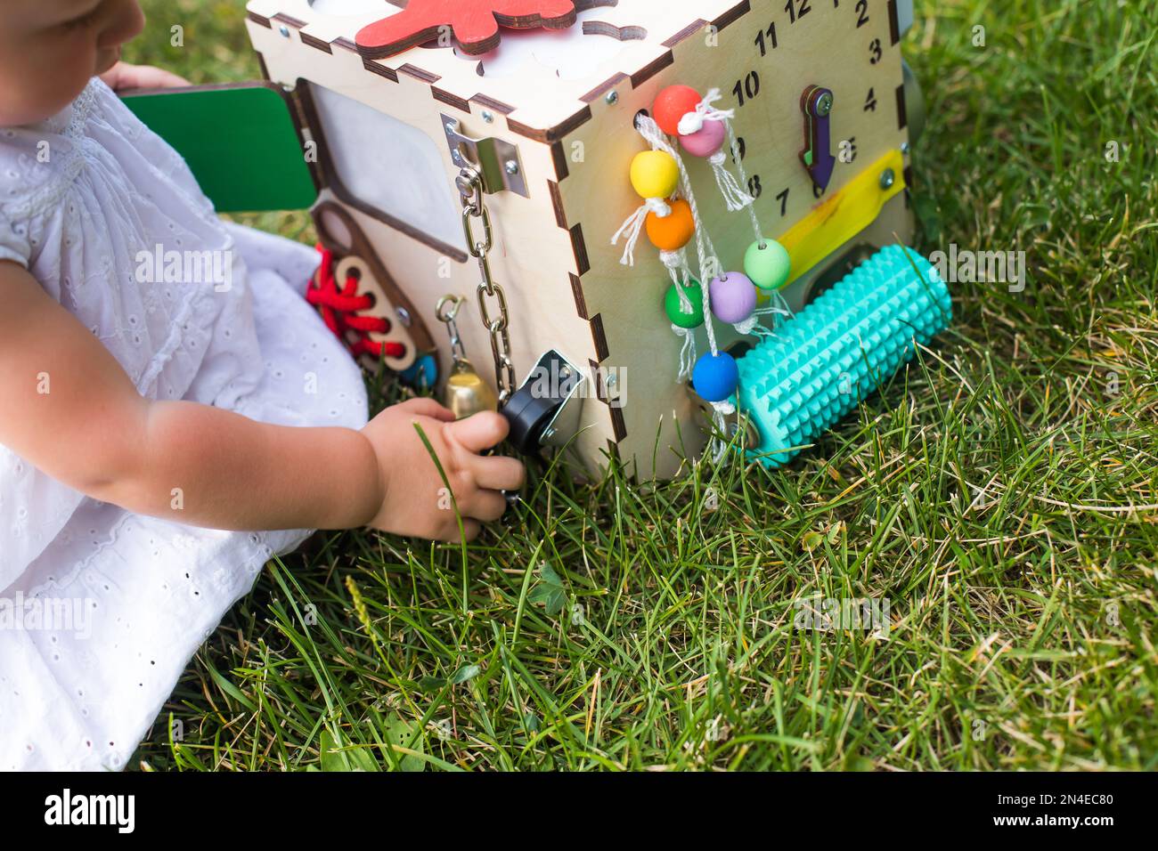 The child spins the wheel on the educational toy.cube. Happy toddler baby girl is playing with a ...