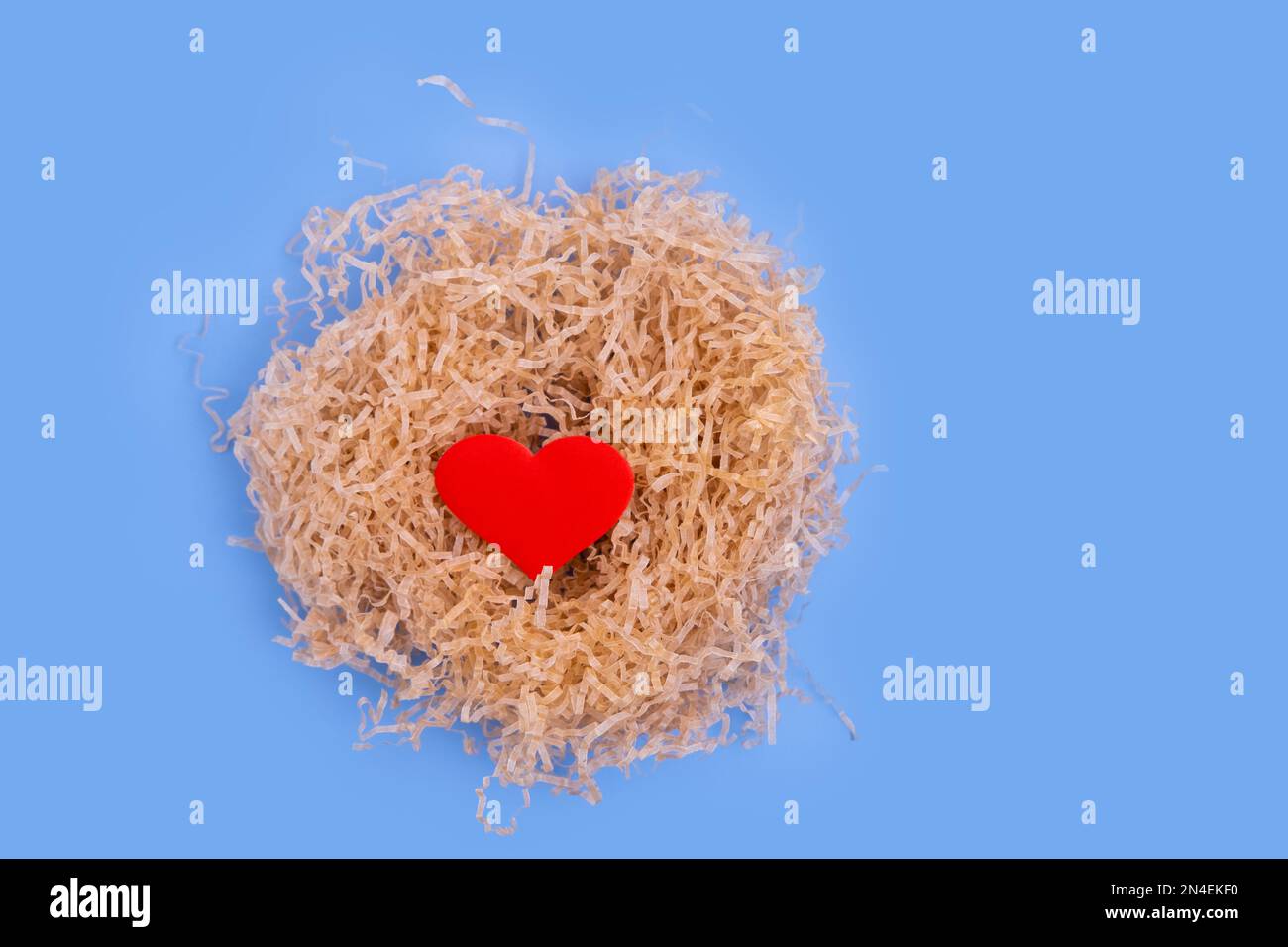 A red heart in a homemade nest on a blue background. Family values ...