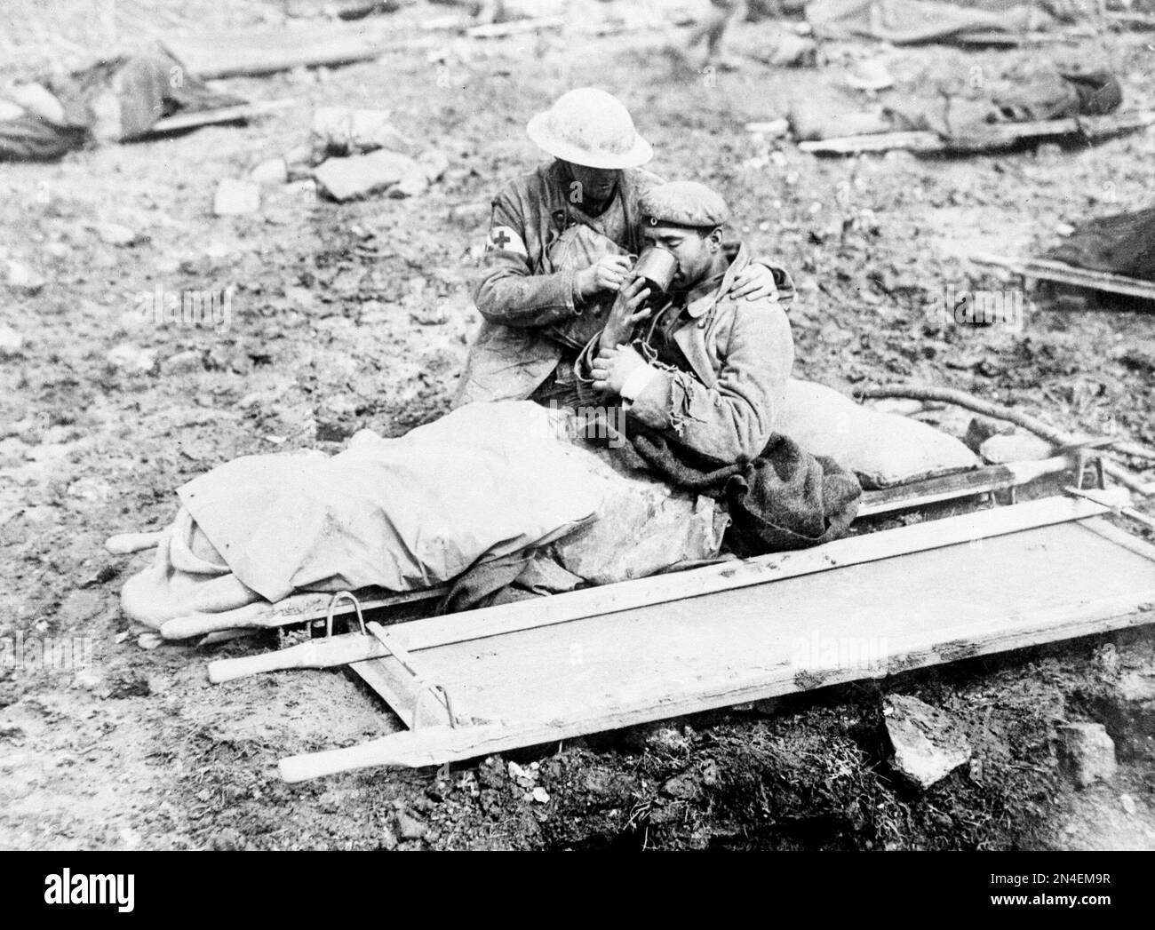 A French Red Cross worker helps a German soldier to sit up and drink a ...