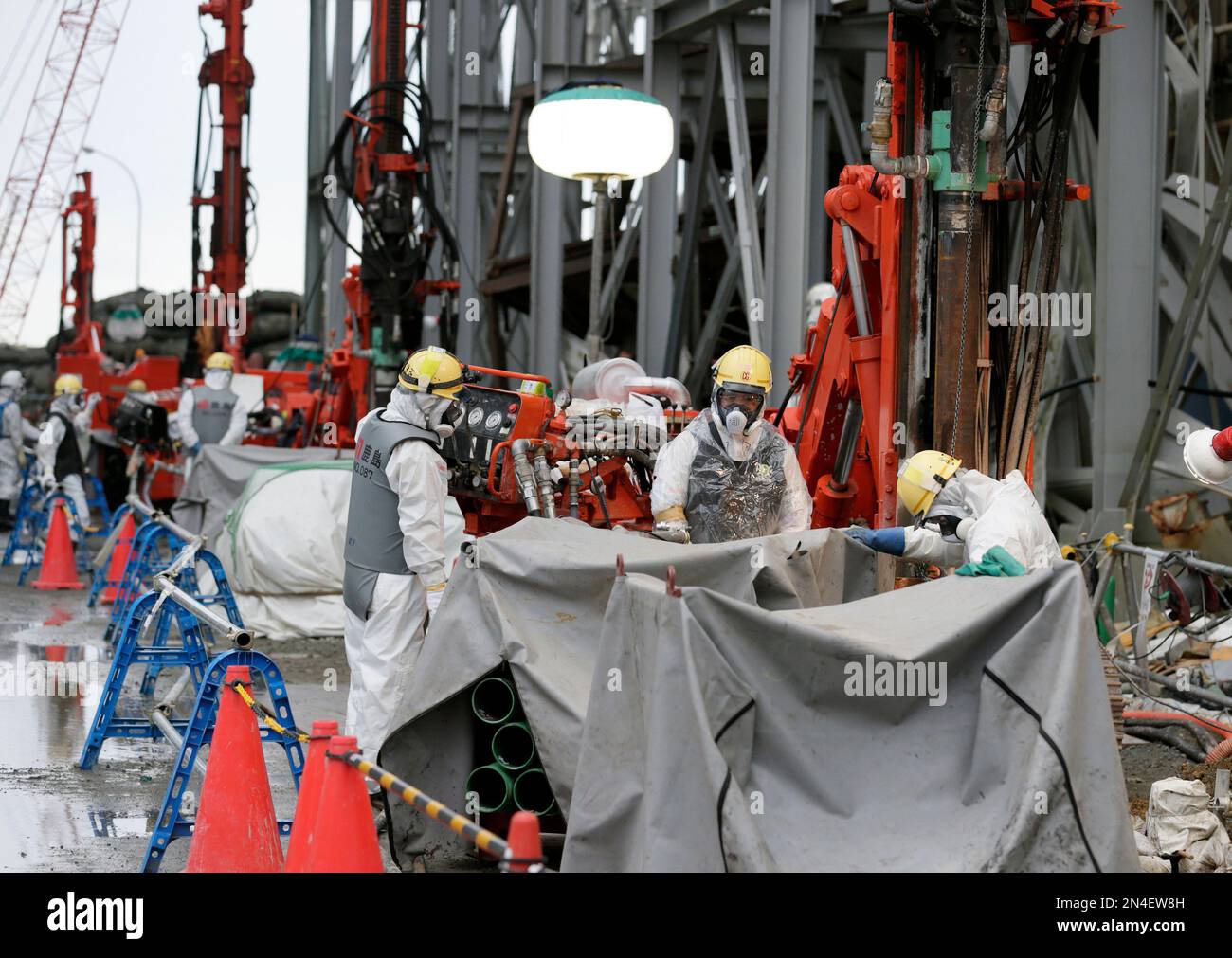 Workers handle pipes which will be used to create a frozen underground ...