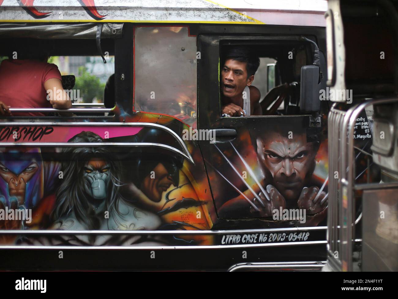 A Filipino jeepney driver assistant calls for passengers during traffic ...