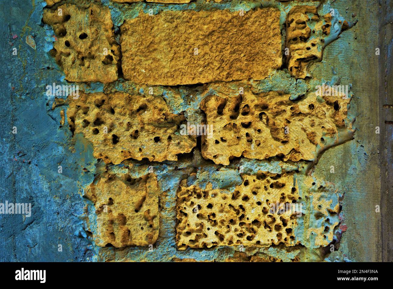 Old yellow wall of limestone with natural holes and grey cement seams ...