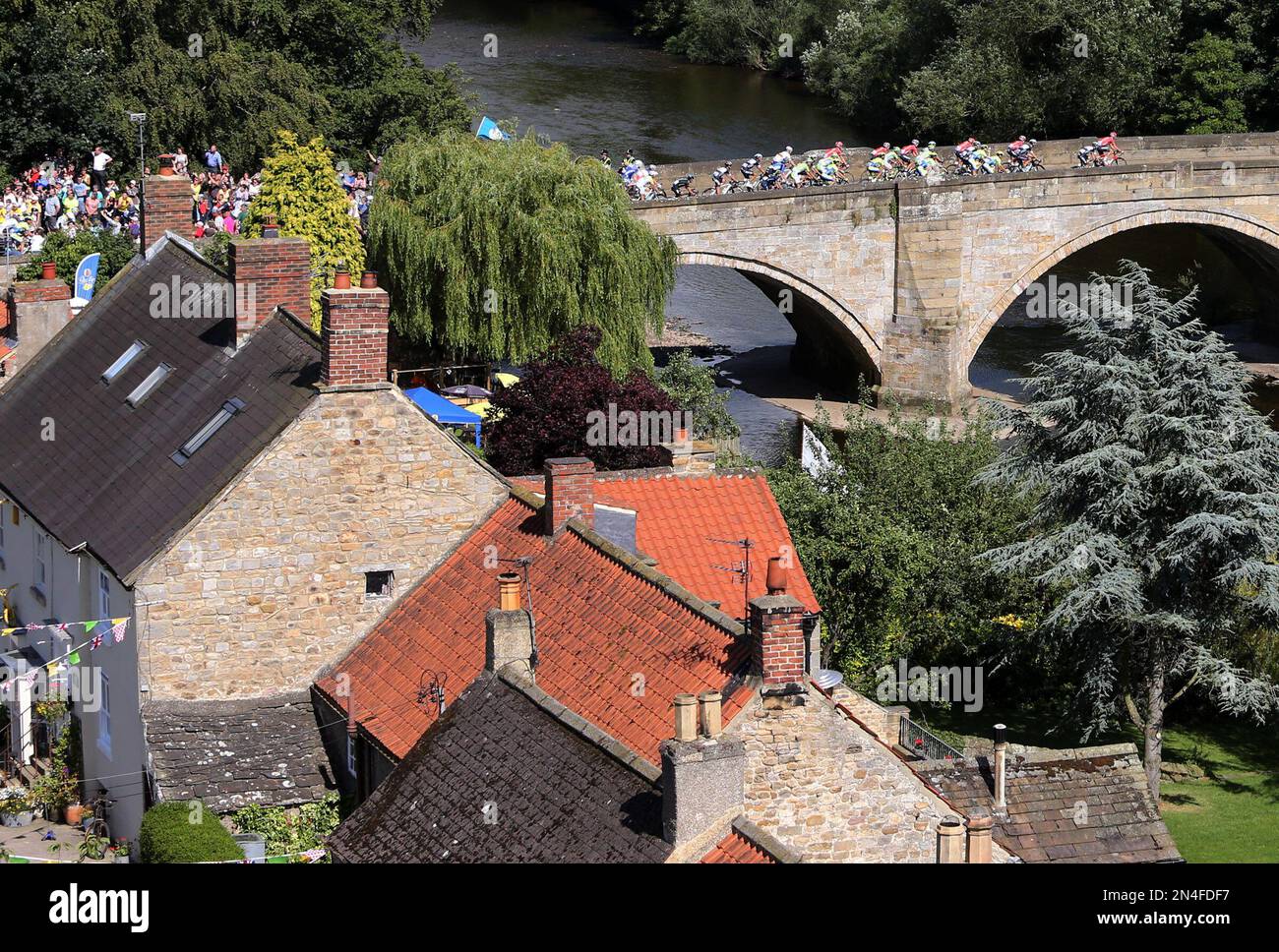 Tour De France riders cross a bridge near the village of West Tanfield ...