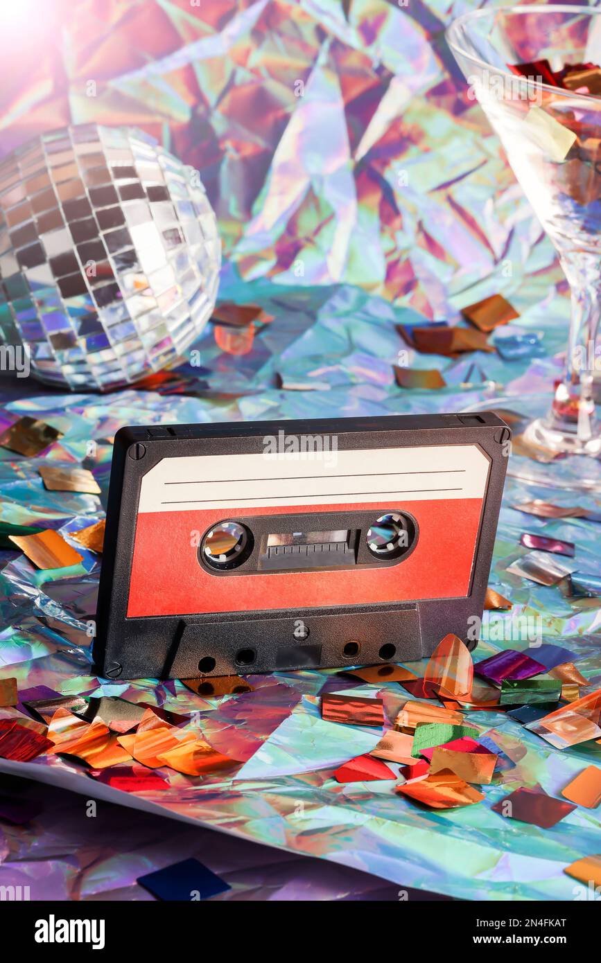 old cassette tape, disco ball and cocktail glass on crumpled neon ...